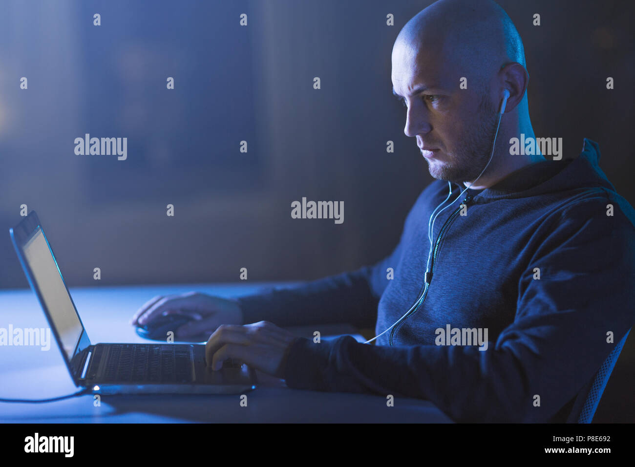hacker in earphones typing on laptop in dark room Stock Photo - Alamy