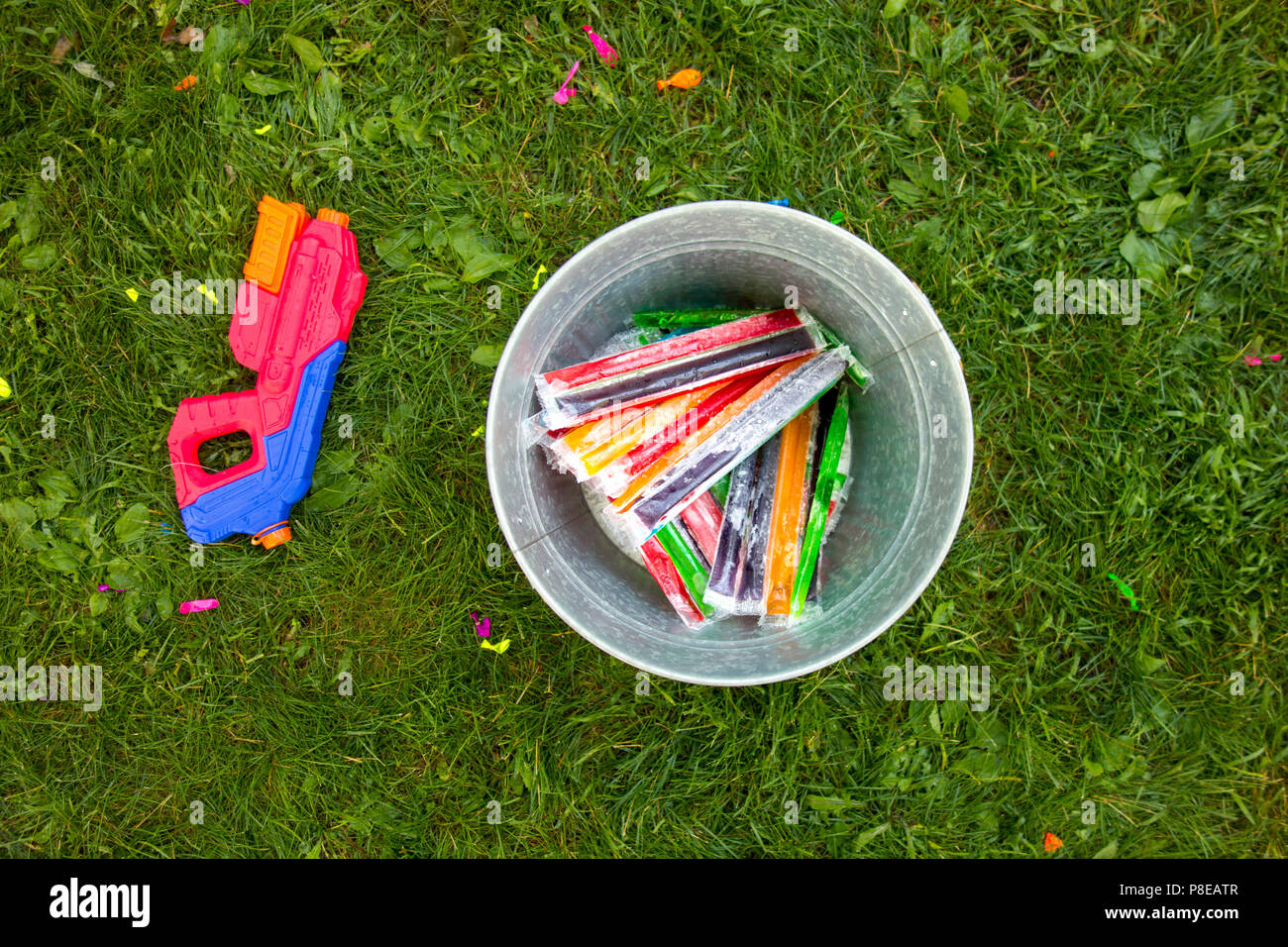 Summertime fun represented by a bucket full of popsicles and a water ...