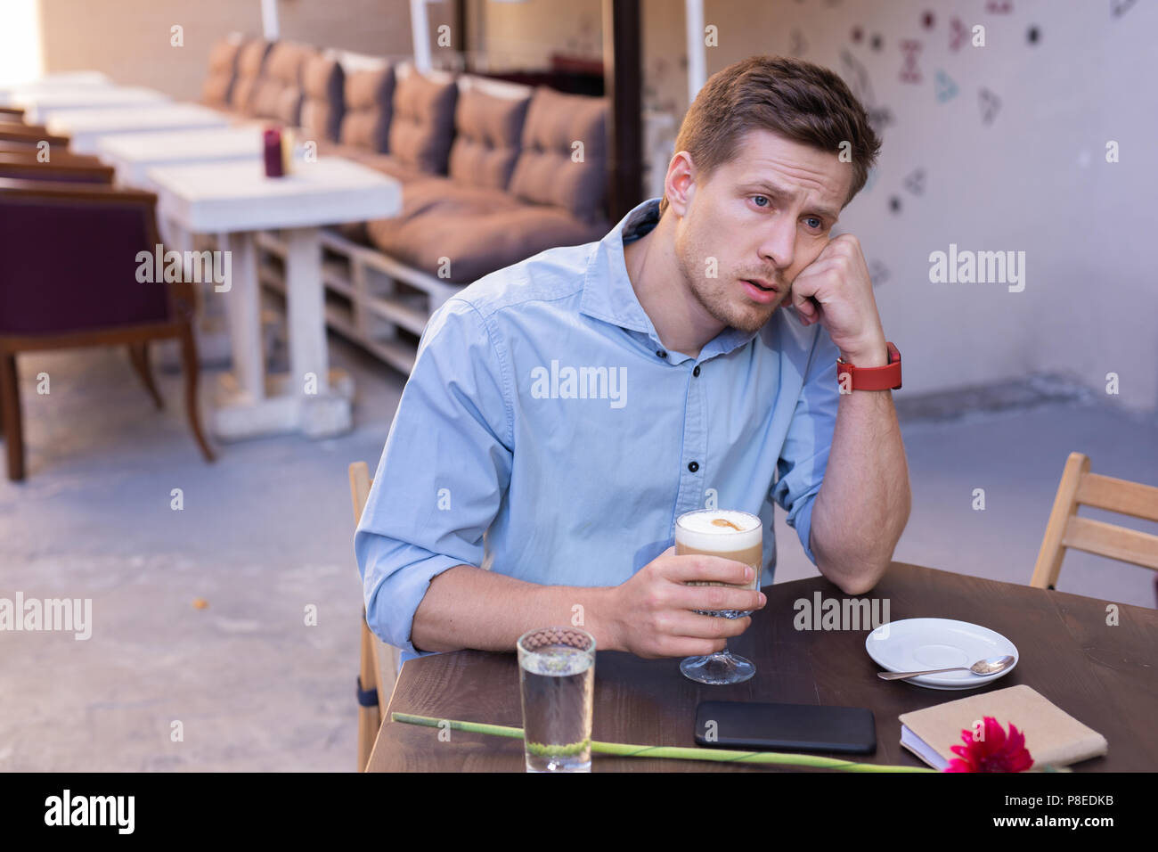 Blue-eyed man feeling bored during coffee break Stock Photo - Alamy