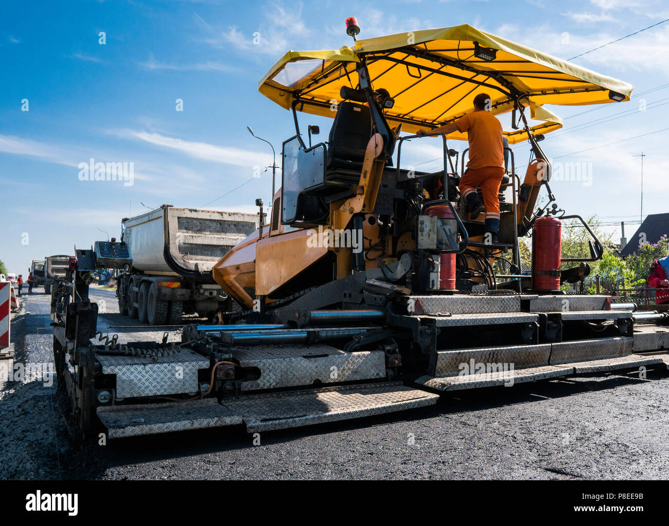 Worker operating asphalt paver machine during road construction and ...