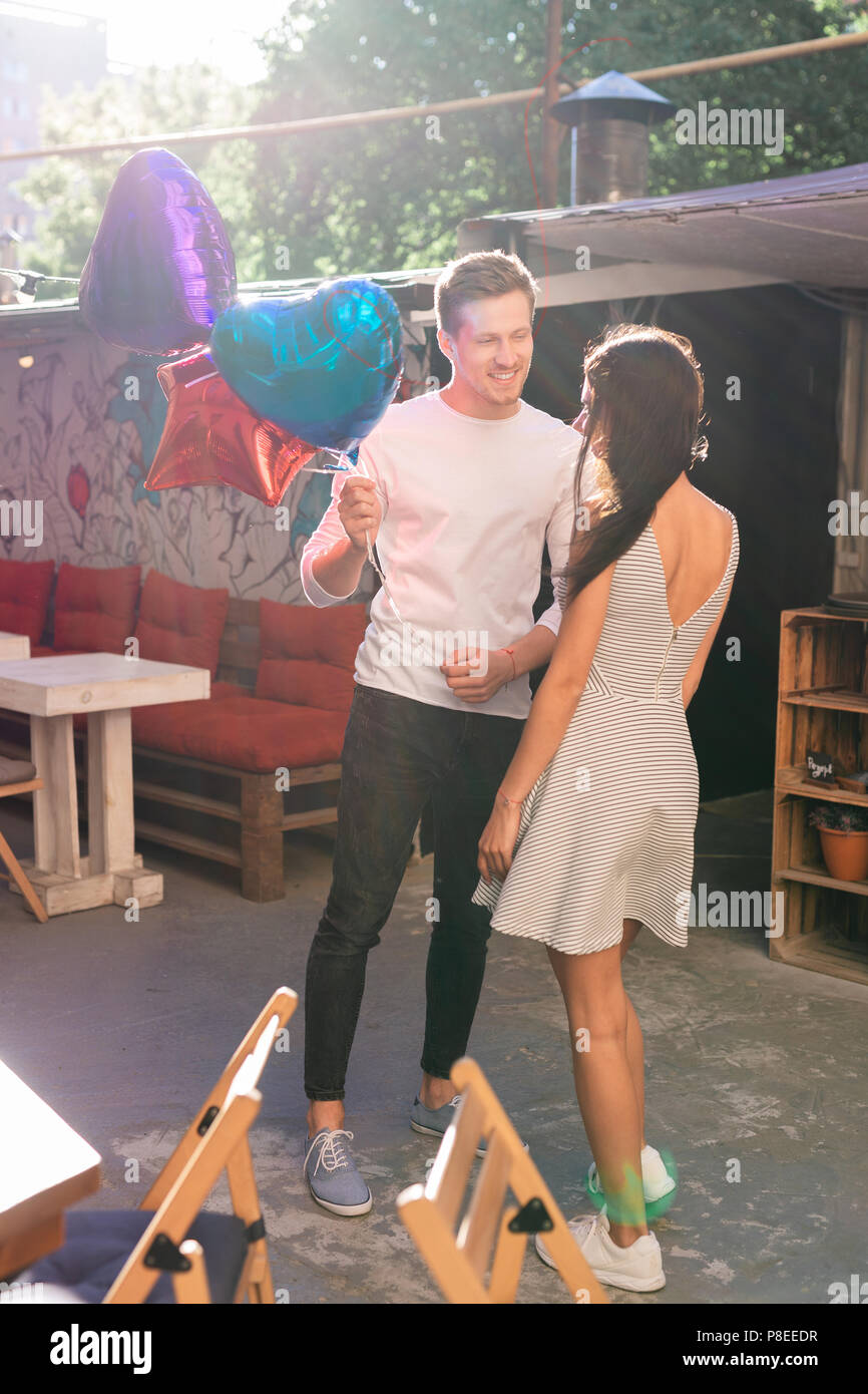 Handsome caring man presenting colorful air balloons Stock Photo - Alamy