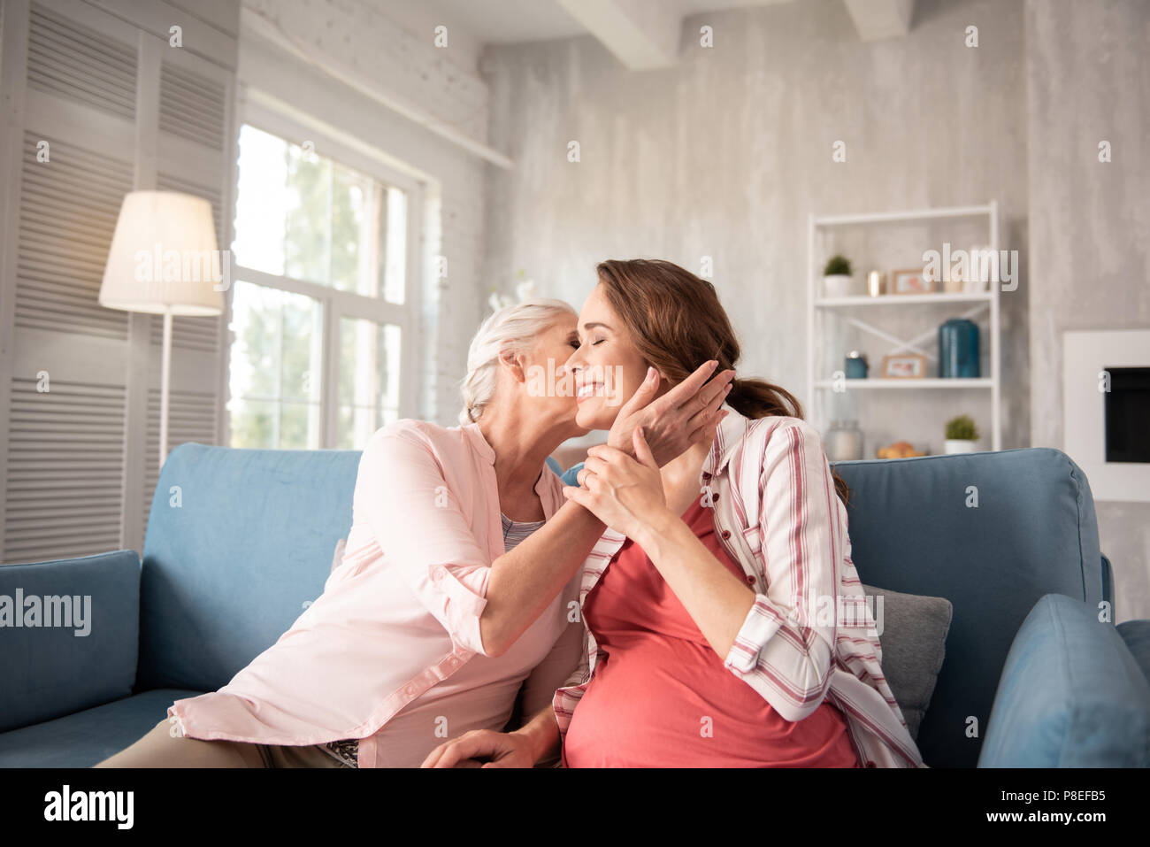 Caring loving mother feeling warm kissing her anticipating daughter ...