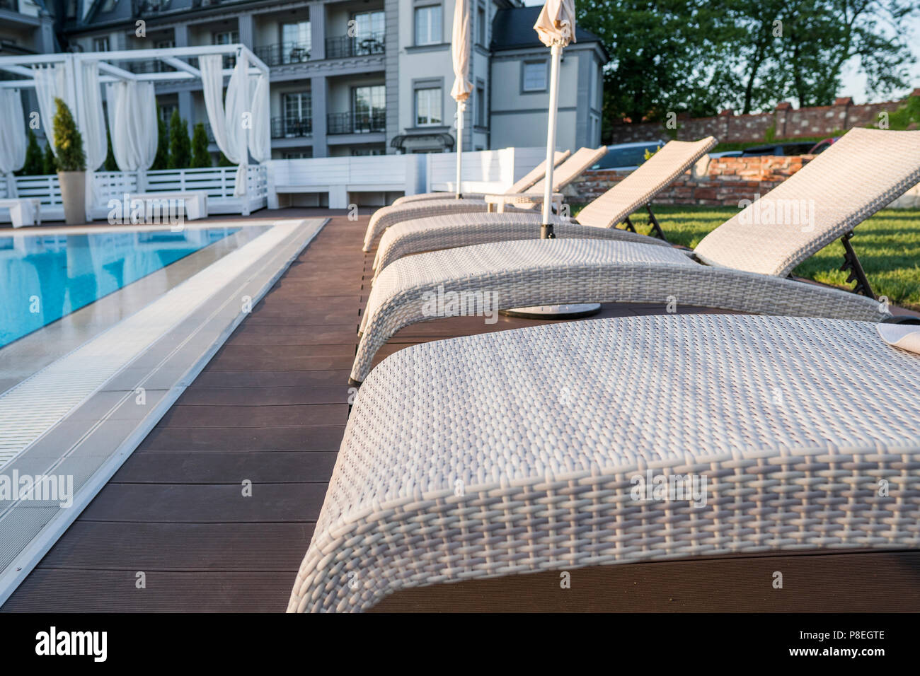Sunbed near pool with clean water in sunny day Stock Photo - Alamy