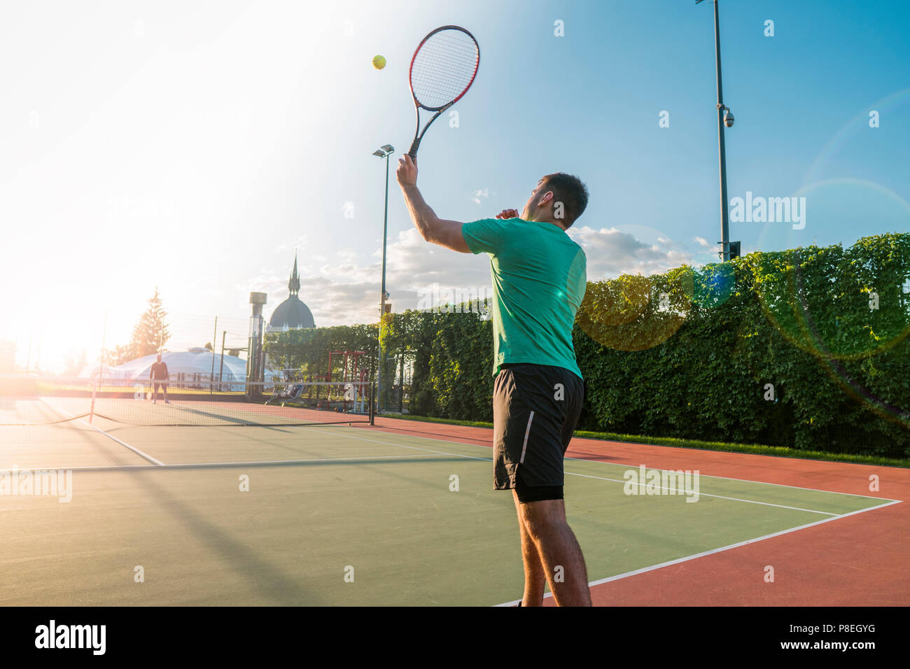 Man is playing tennis on tennis court outdoors in sunset Stock Photo ...