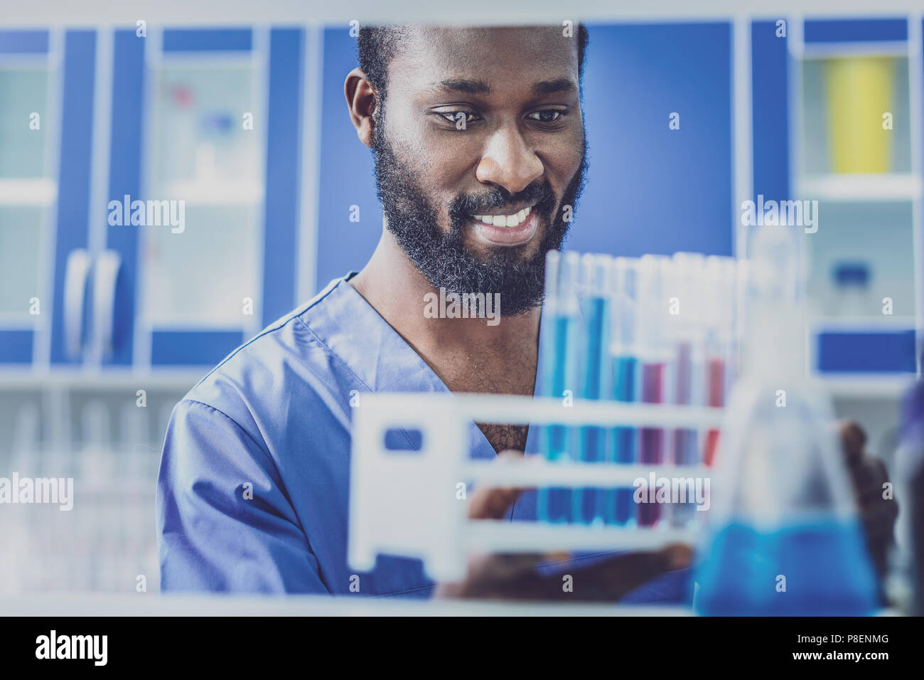 Dark-eyed promising chemist looking at test tubes Stock Photo - Alamy