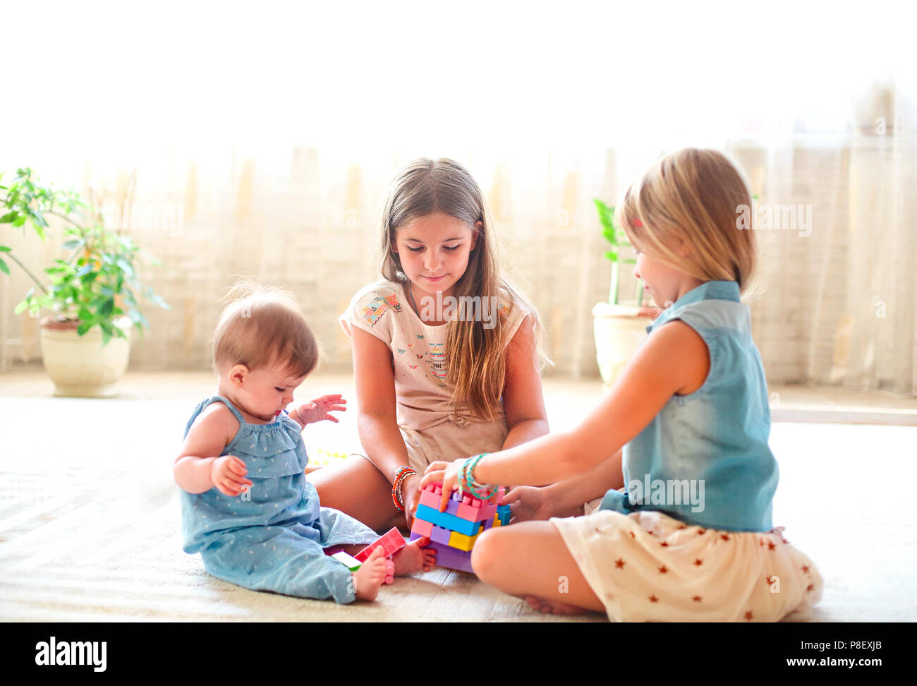 Three cute girl playing together indoors Stock Photo - Alamy