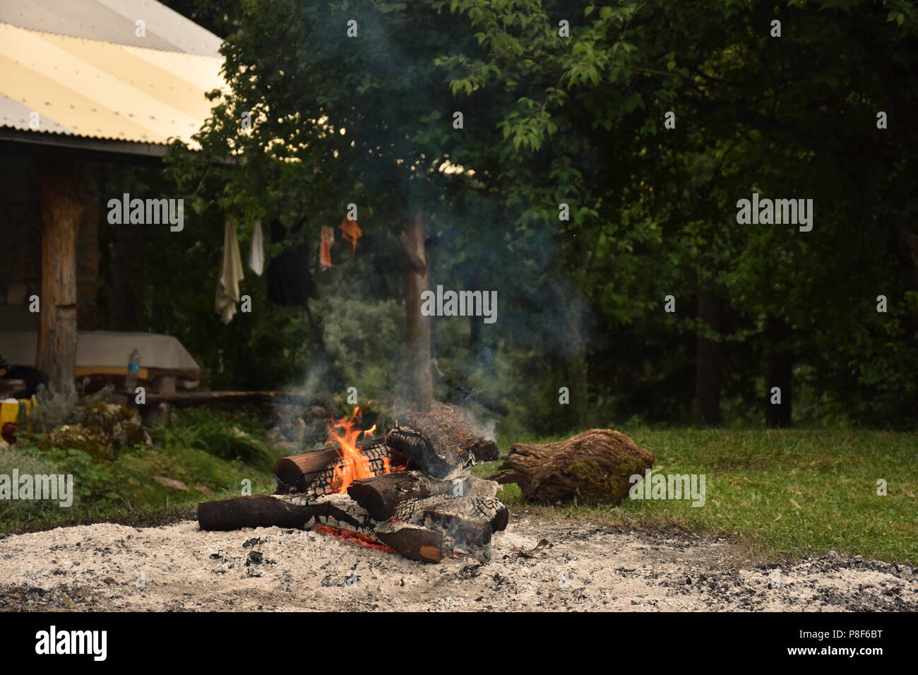 Cabin in the woods with campfire in front of it Stock Photo - Alamy