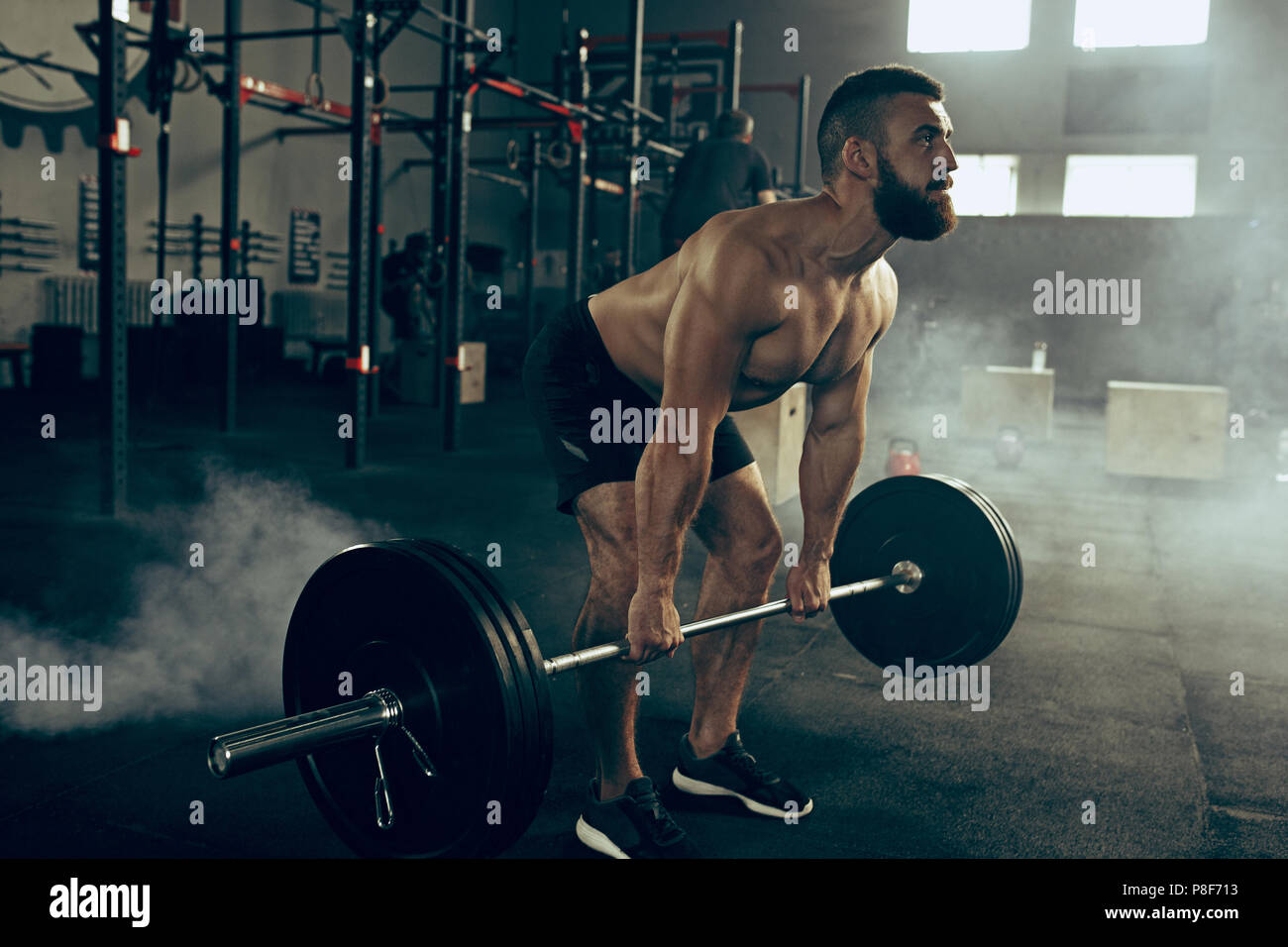 Fit young man lifting barbells working out in a gym Stock Photo - Alamy