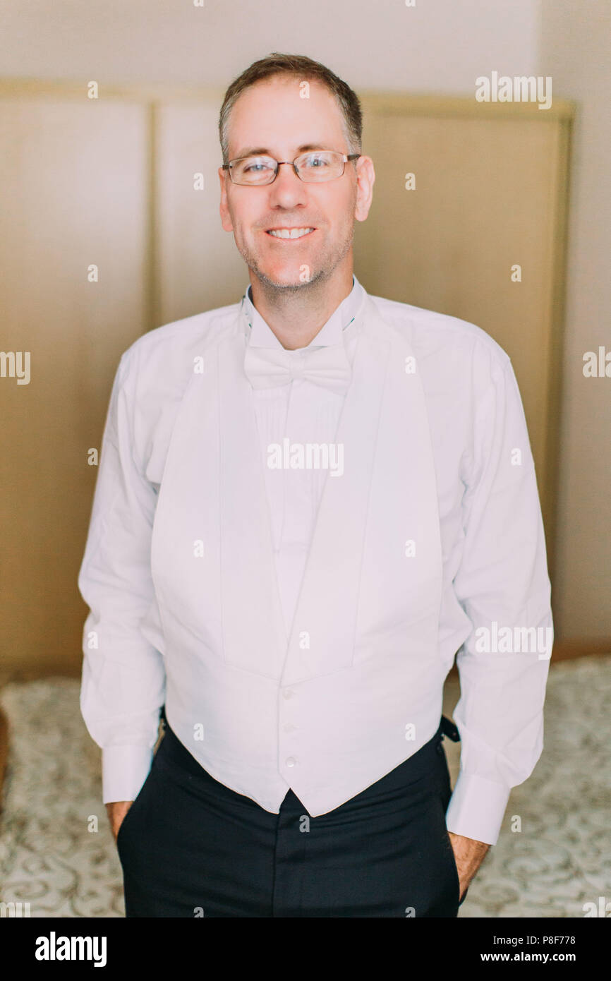 Half-length portrait of the charming smiling groom wearing glasses ...