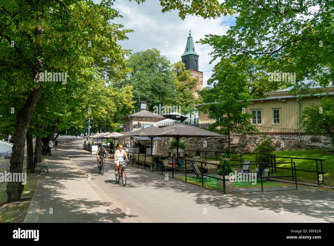 TURKU, FINLAND - 8/7/2018: People riding a bicycle next to Aura river ...