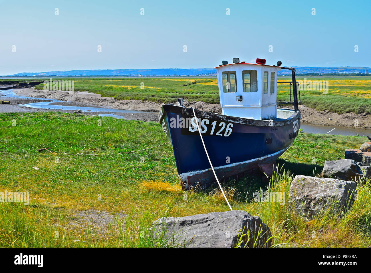 A small pretty fishing boat standing high & dry on the Lougher Estuary ...