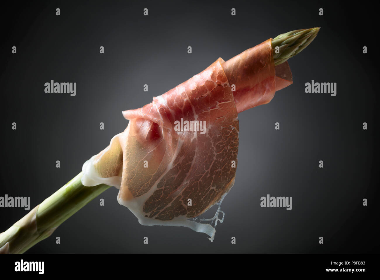 Asparagus wrapped in prosciutto on a dark background Stock Photo - Alamy