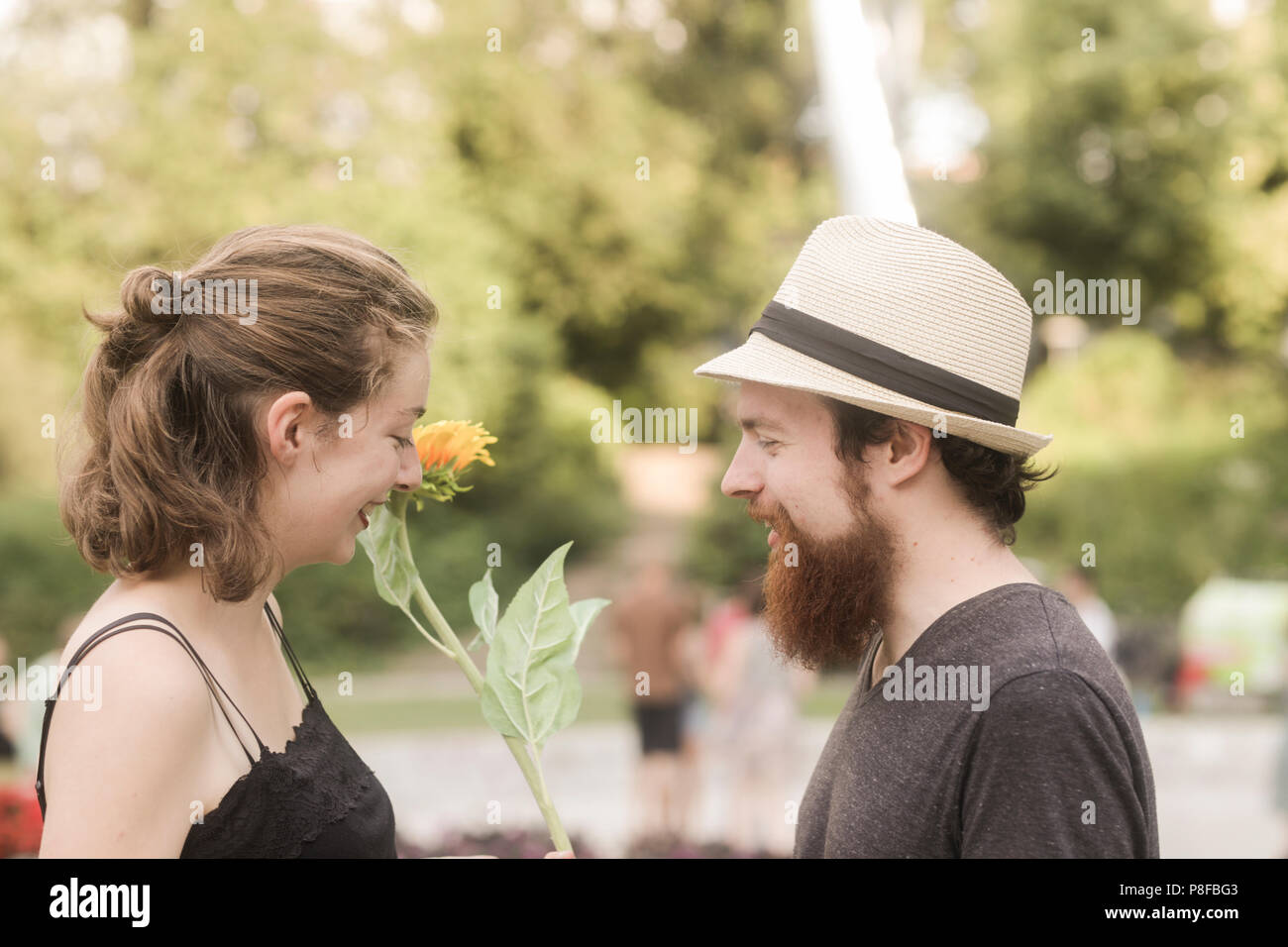 Man standing in a park giving his girlfriend a sunflower Stock Photo ...