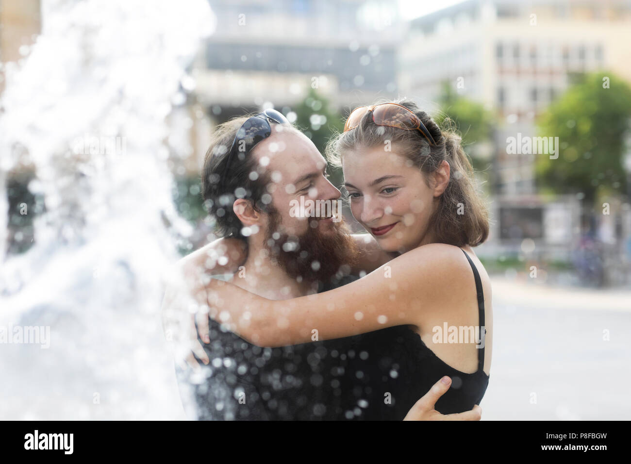 Couple standing by a water fountain hugging Stock Photo - Alamy