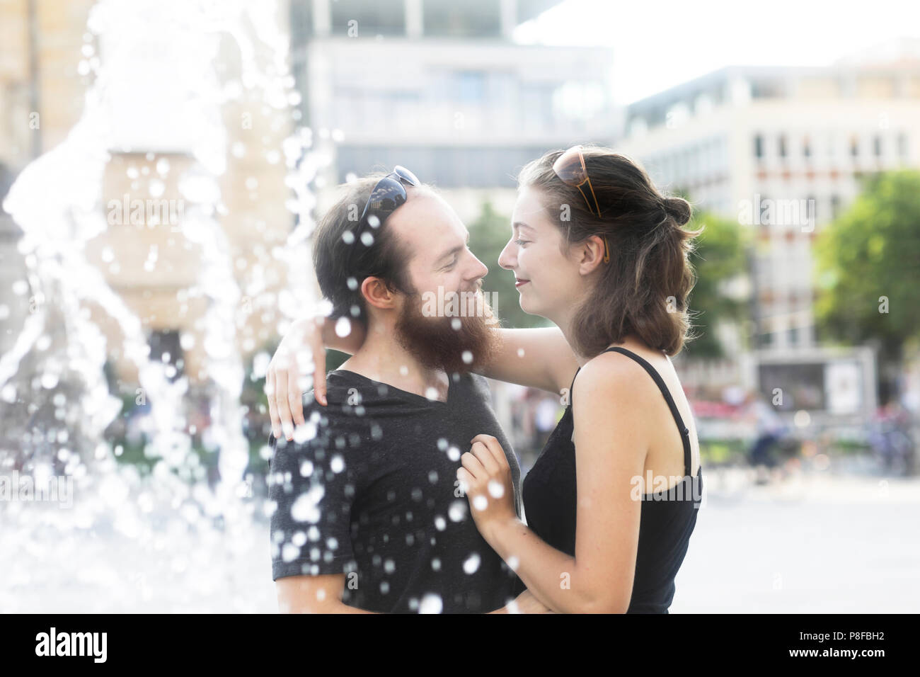 Couple standing by a water fountain hugging Stock Photo - Alamy