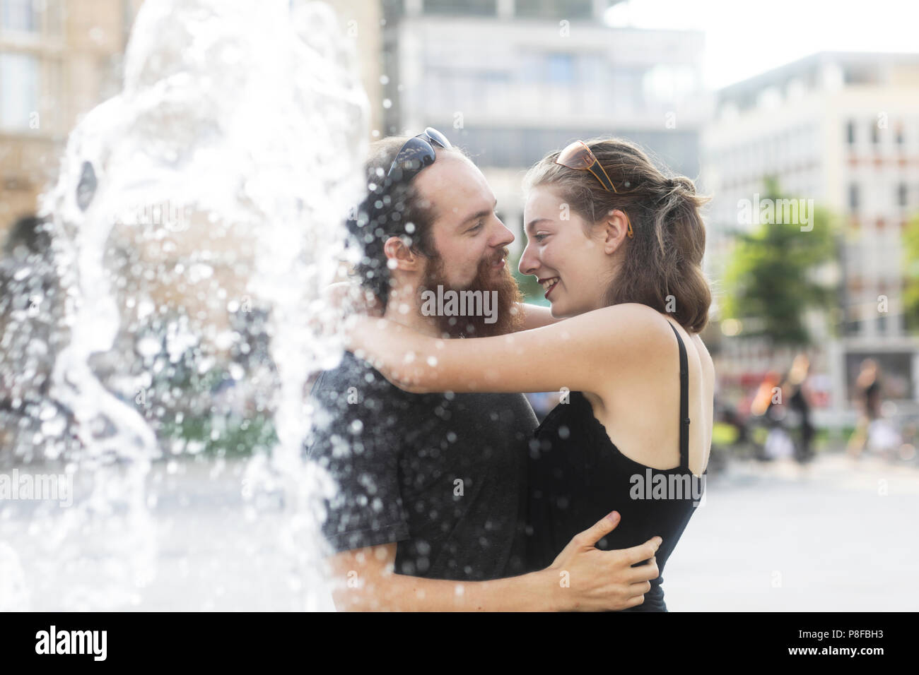 Couple standing by a water fountain hugging Stock Photo - Alamy