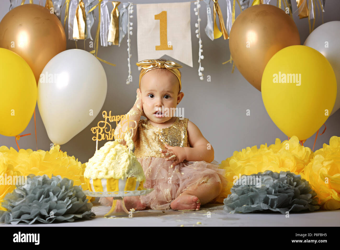 Adorable and cute girl in beautiful dress crying on her first birthday ...