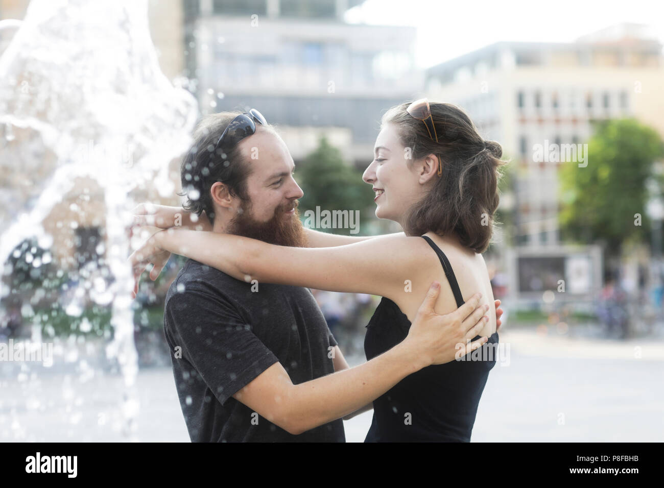 Couple standing by a water fountain hugging Stock Photo - Alamy