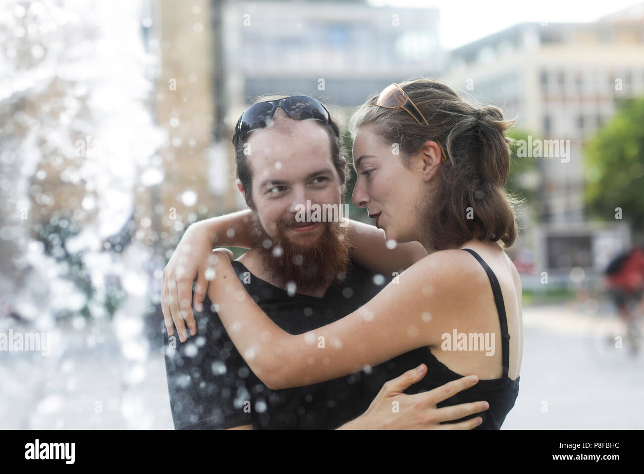 Couple standing by a water fountain hugging Stock Photo - Alamy