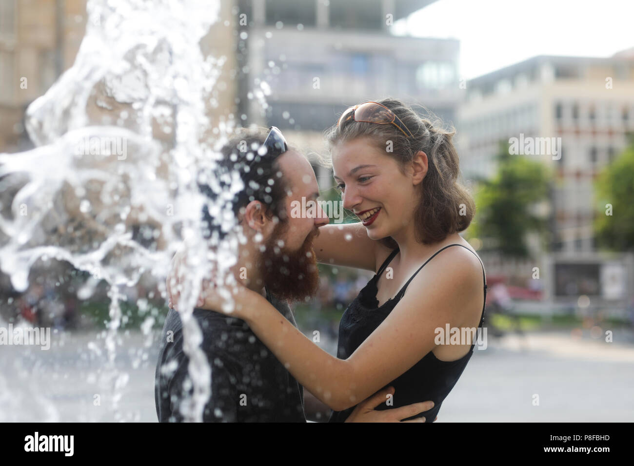 Couple standing by a water fountain hugging Stock Photo - Alamy