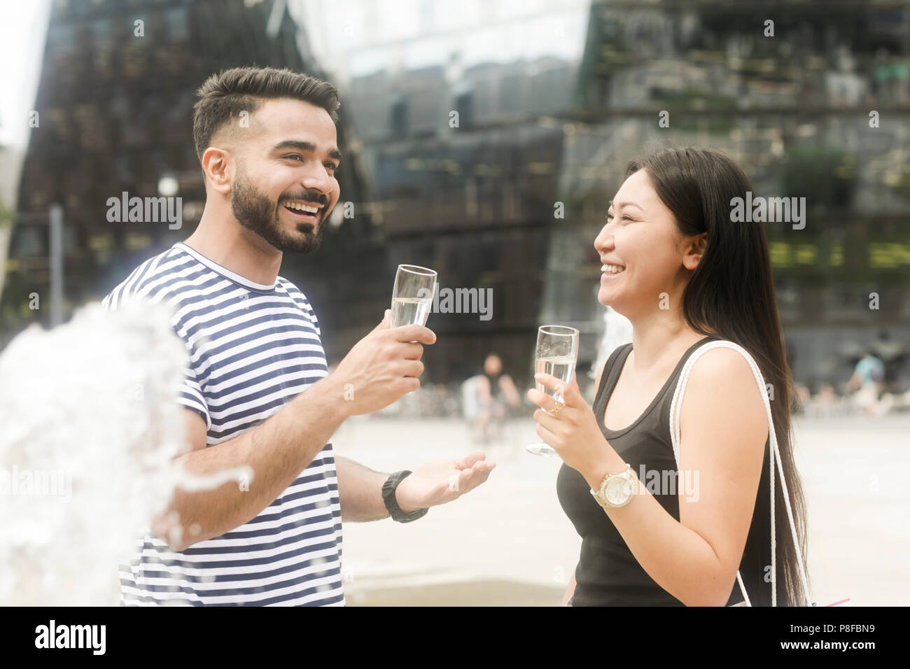 Couple standing by a water fountain making a celebratory toast Stock ...