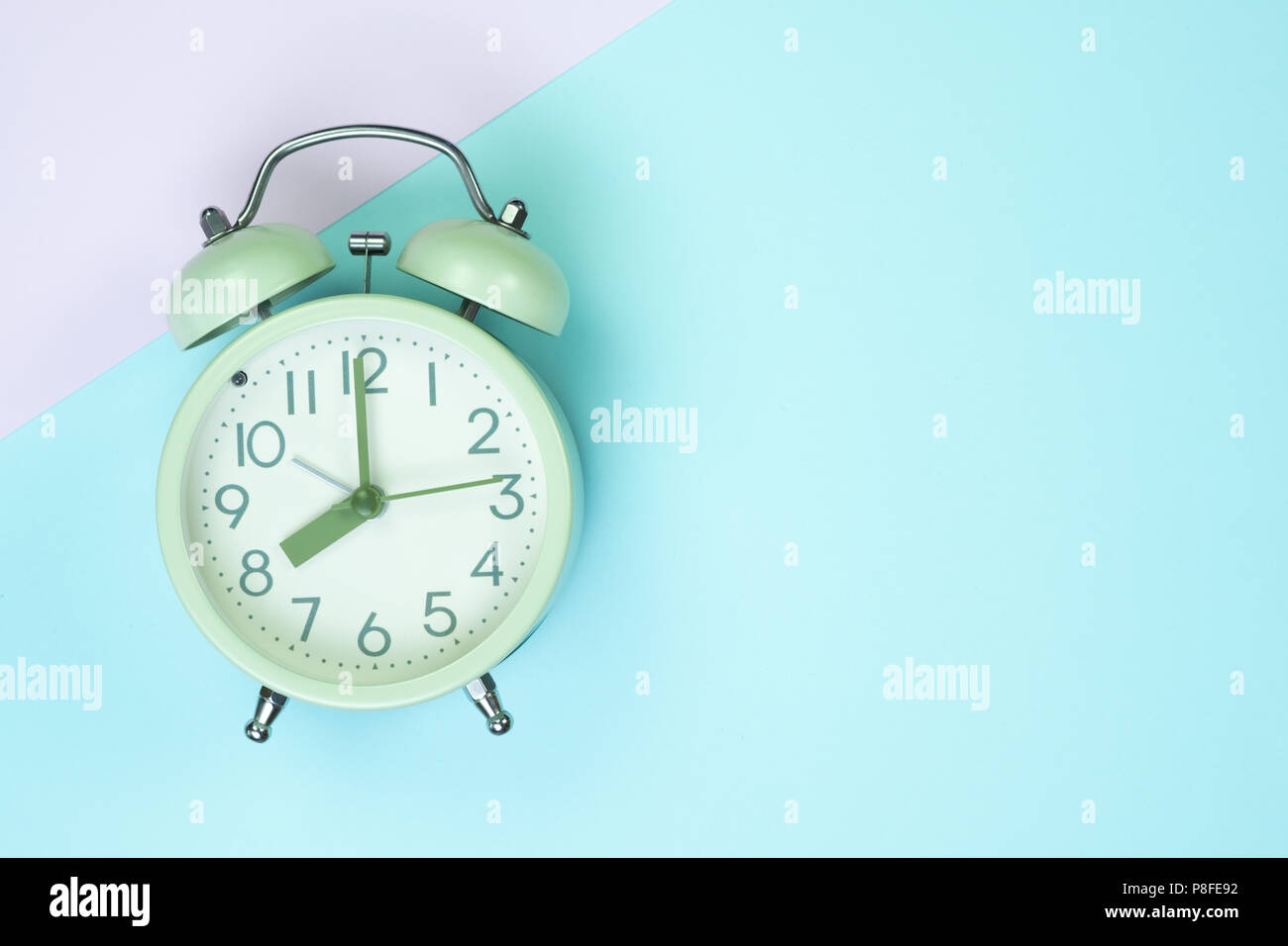 Flat lay vintage alarm clock on sweet pastel colored paper top view ...