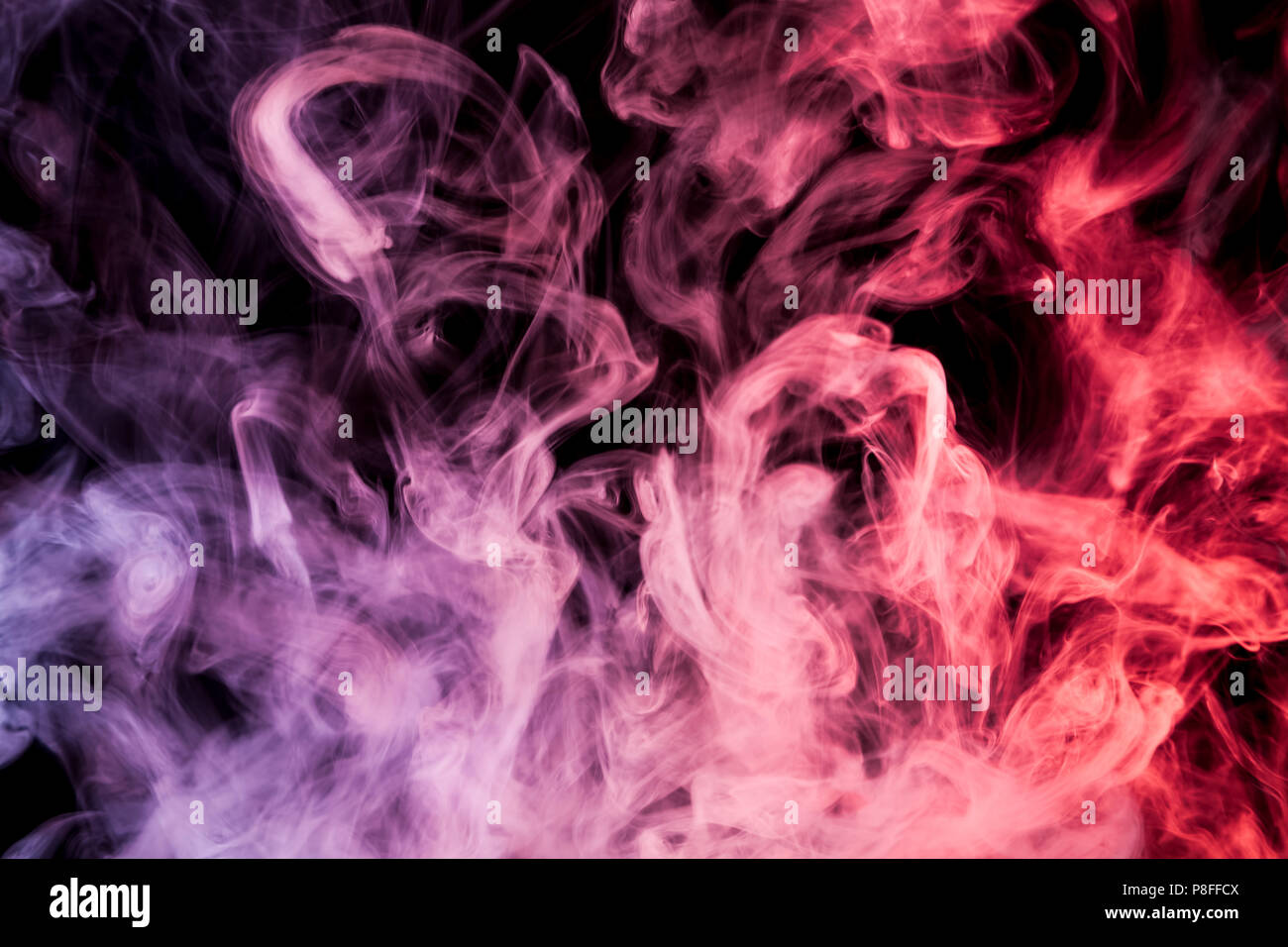 Dense multicolored smoke of pink, red and purple colors on a black ...