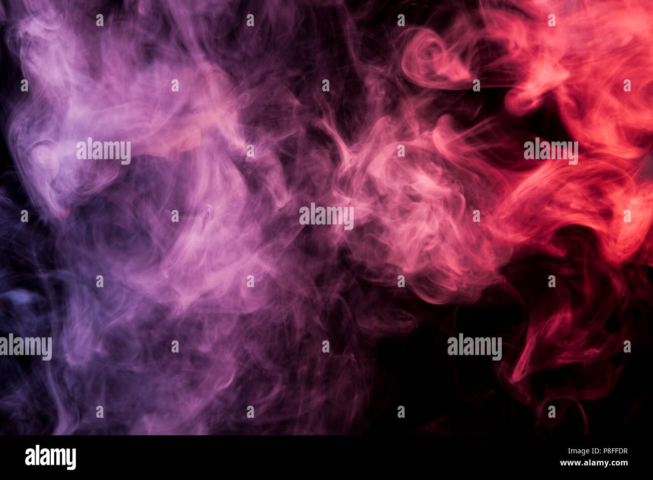 Dense multicolored smoke of pink, red and purple colors on a black ...