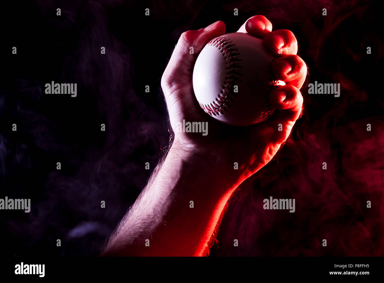 Close-up of a strong male hand holding a white baseball ball against a ...