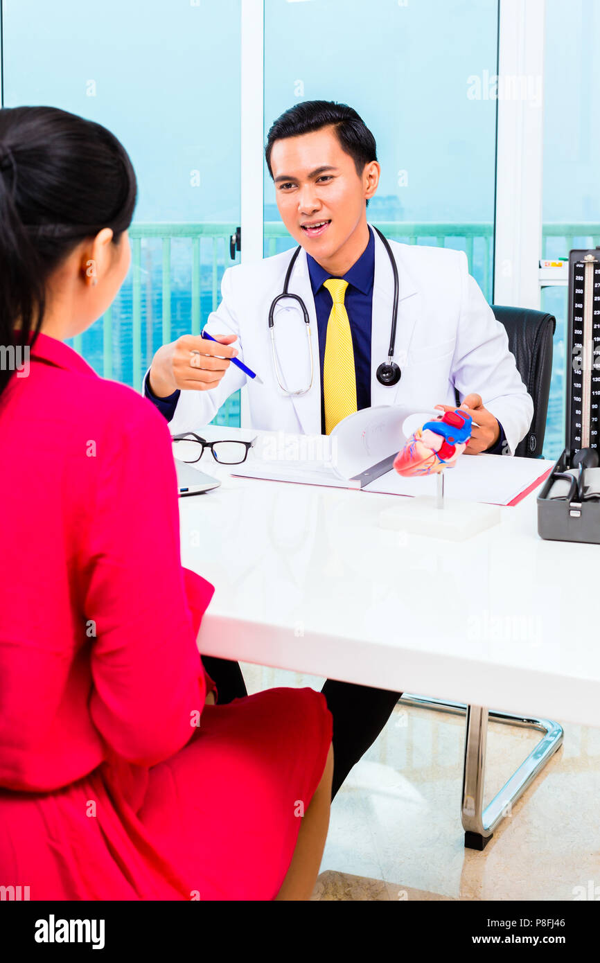 Asian doctor giving patient medical advice in practice or office Stock ...