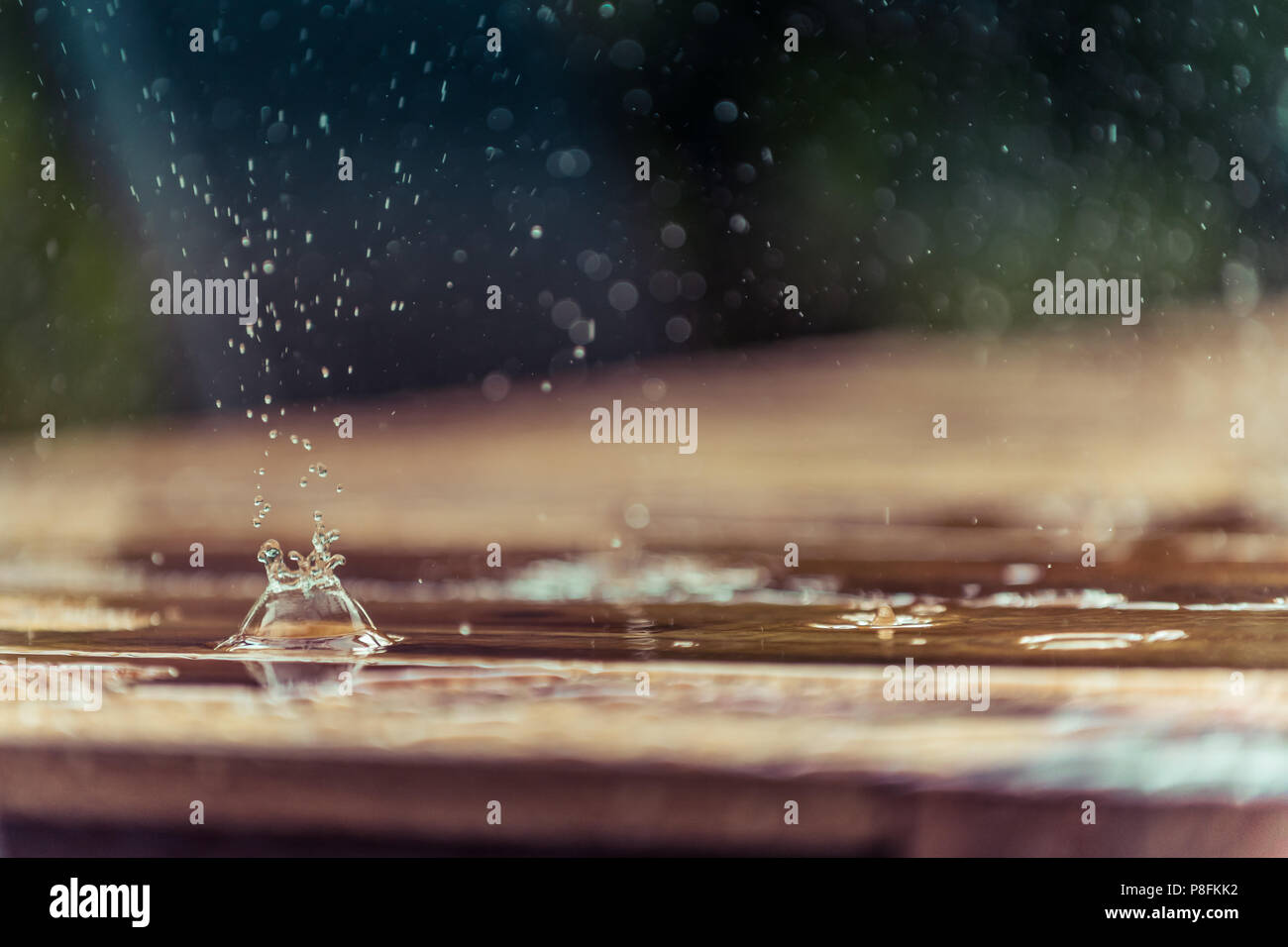 Raindrop splashing into puddle of water Stock Photo - Alamy