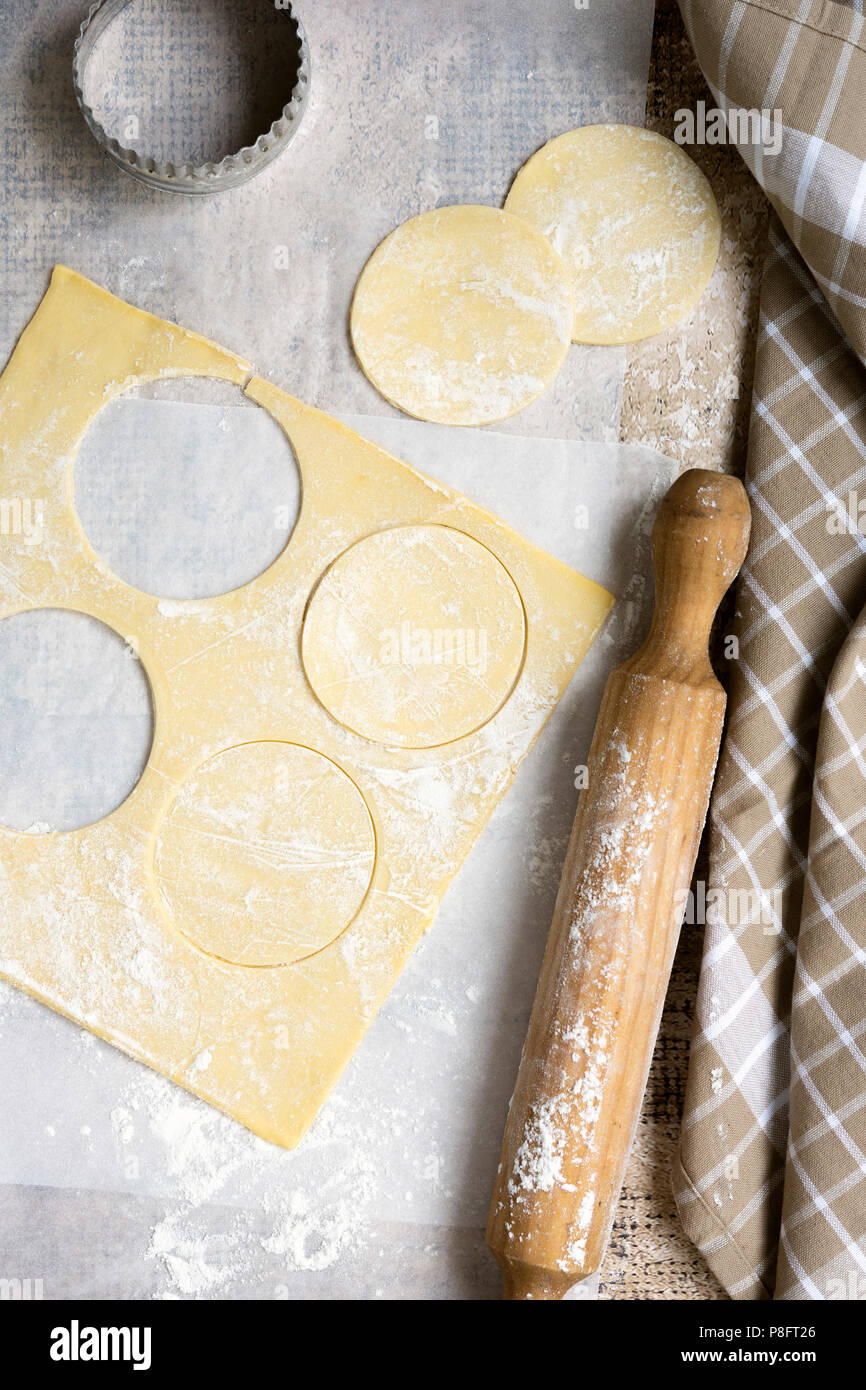 Round circles of shortcrust pastry cut from a sheet and a rolling pin ...