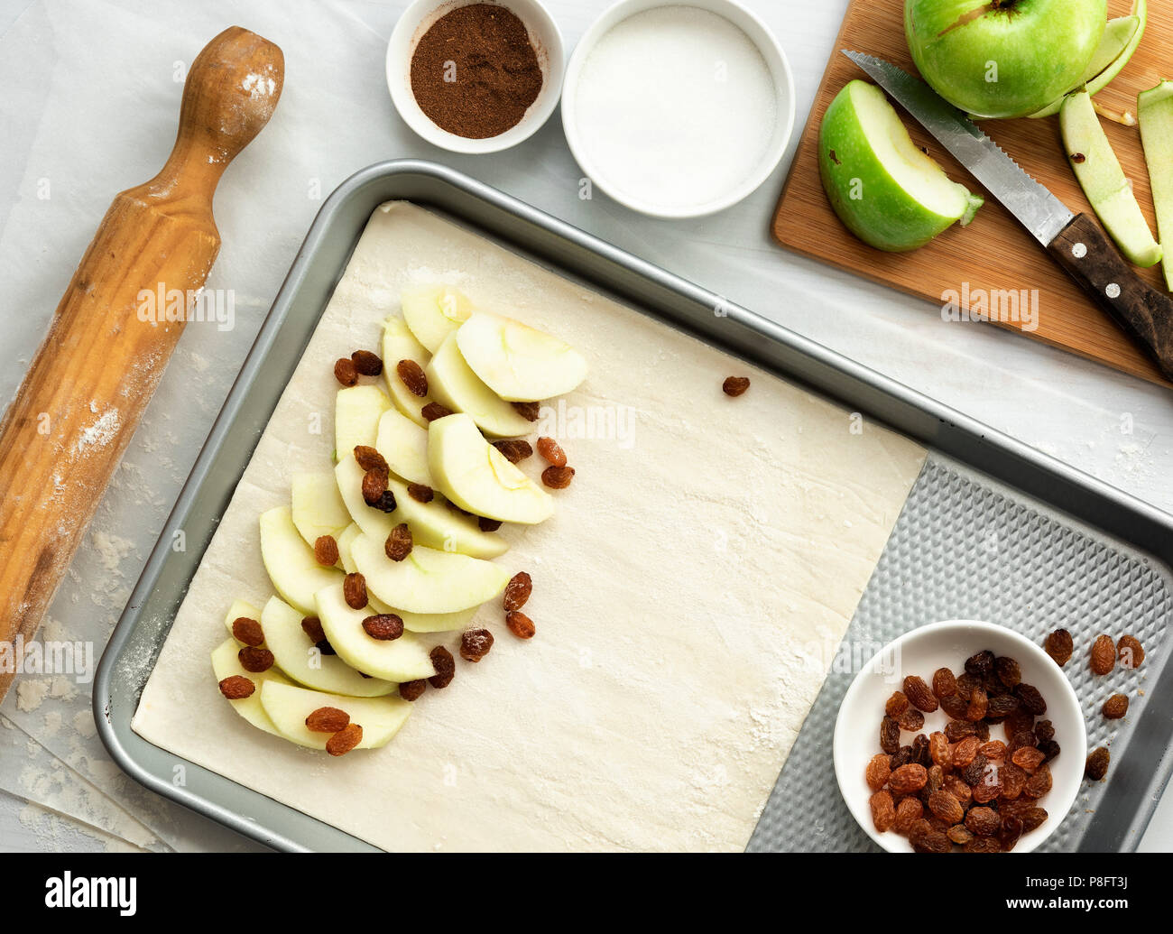 Preparation of apple strudel, apple slices and sultanas on a pastry ...