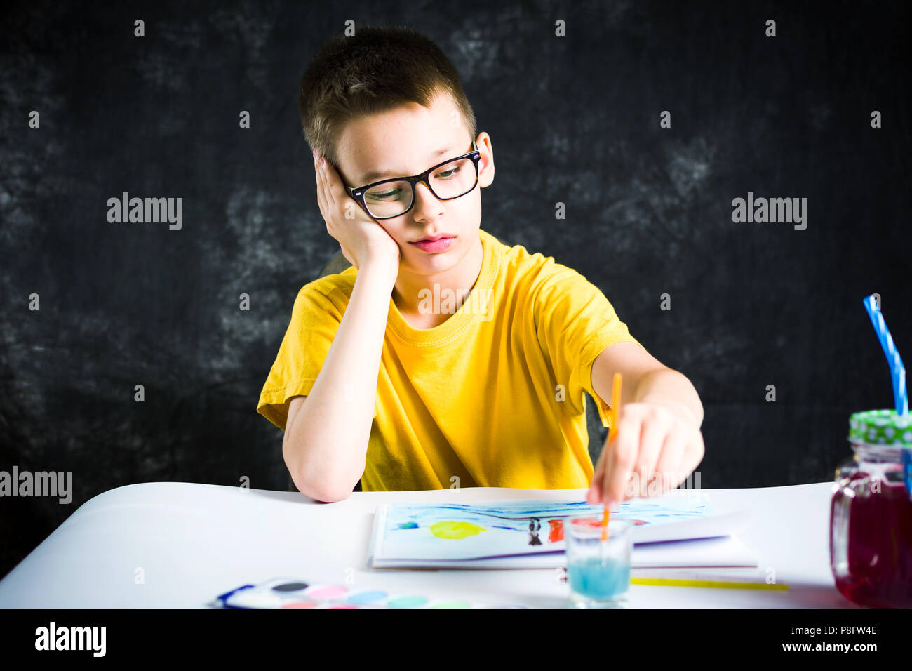 Bored schoolboy making a colorful drawing at home Stock Photo - Alamy