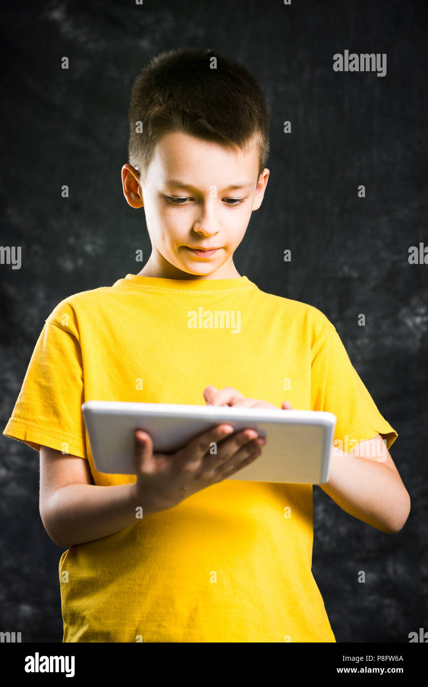 Boy holding a white tablet device against dark background Stock Photo ...