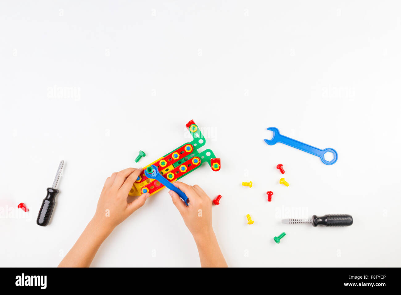 Child's hands playing with colorful toys tools on the white background ...