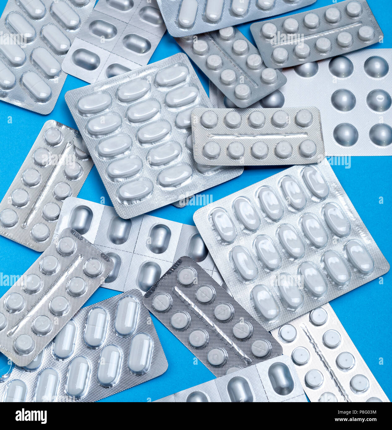 different white tablets in a package are scattered on a blue background ...