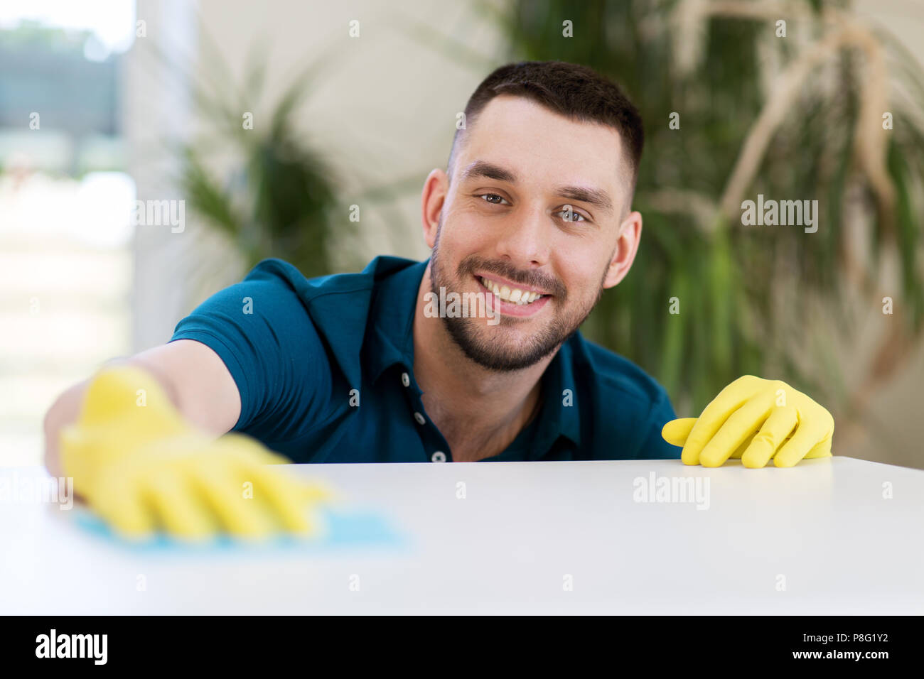 smiling man cleaning table with cloth at home Stock Photo - Alamy
