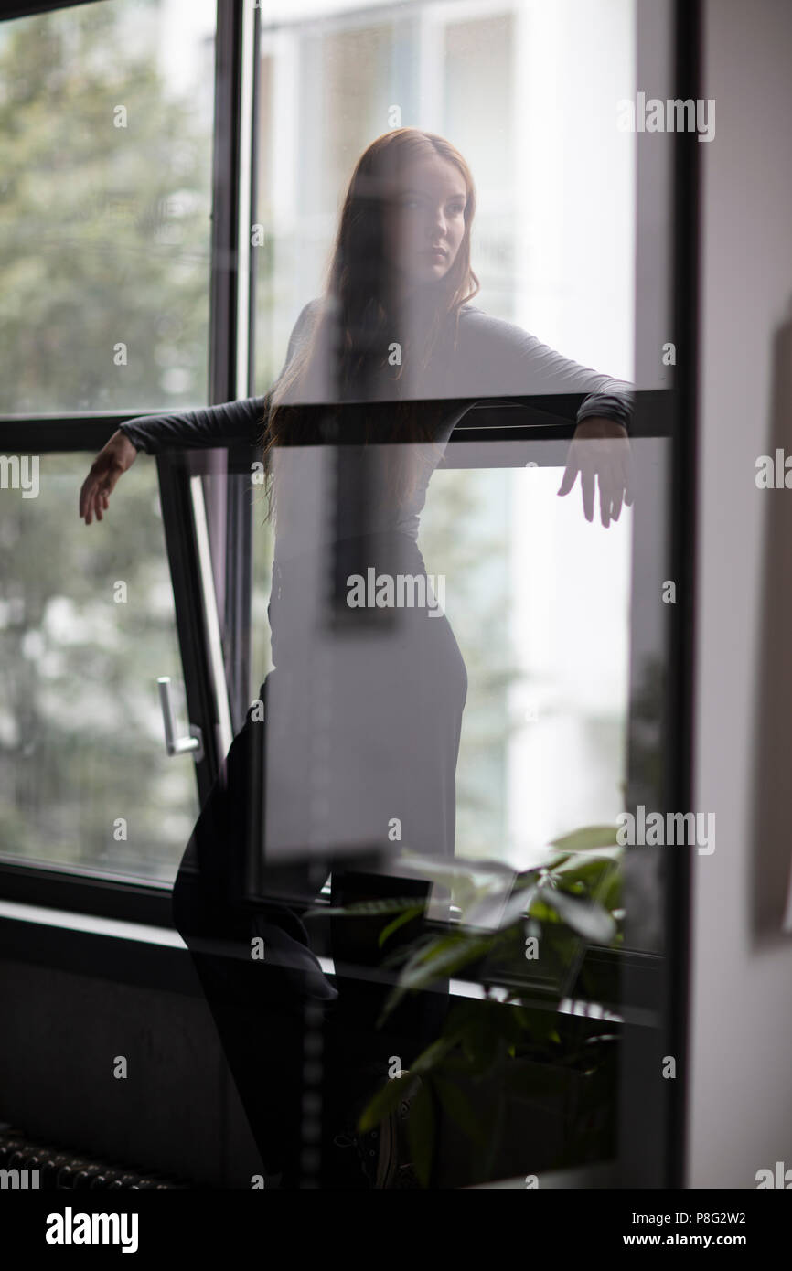 Attractive woman standing between office window and glass in a nearly ...