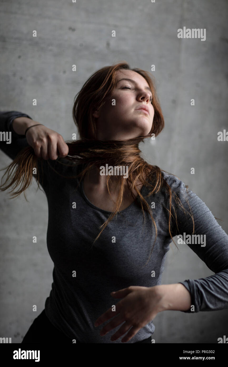Female model tying her own hair around her neck while looking graceful ...