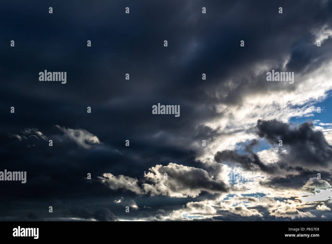 Dramatic rain clouds with a blue sky gap Stock Photo - Alamy