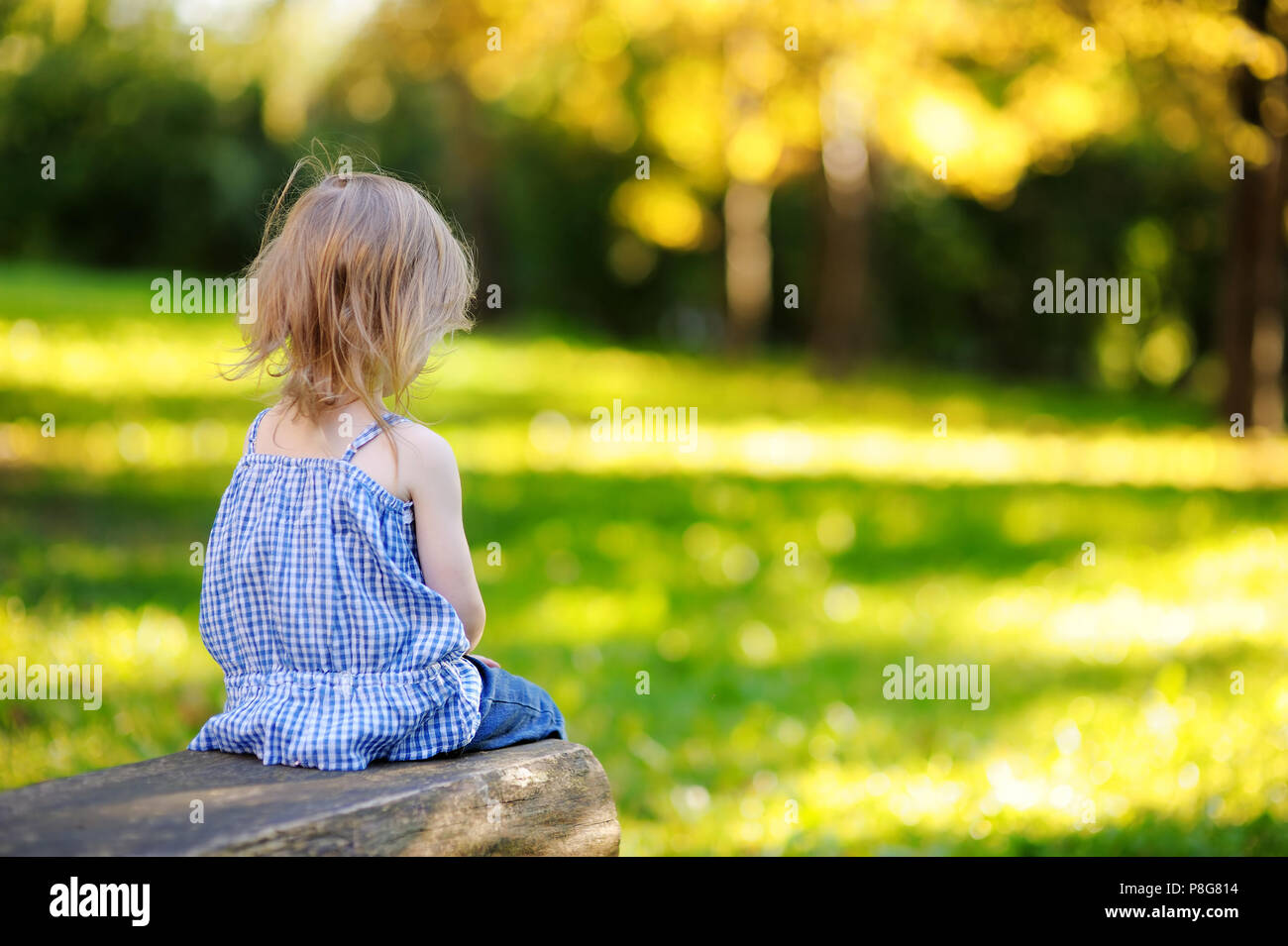 Angry little girl sitting outdoors Stock Photo - Alamy
