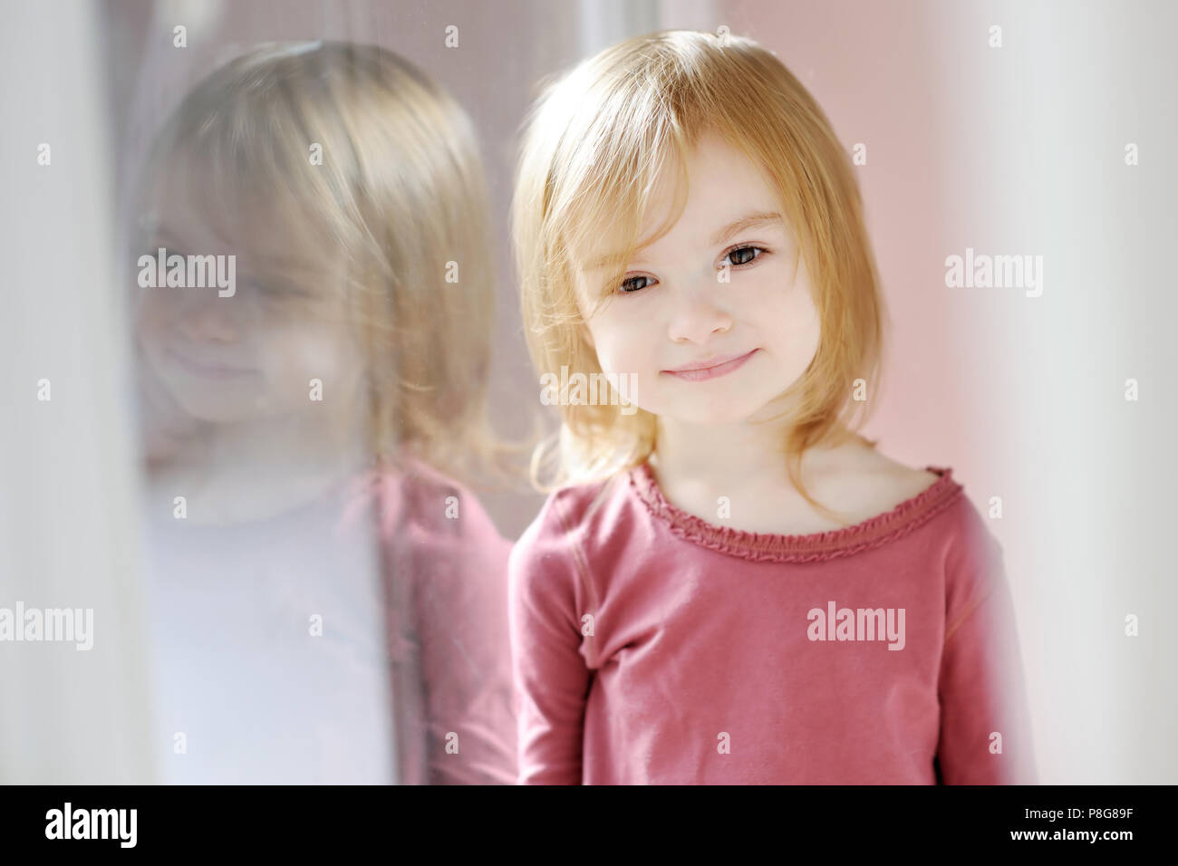 Adorable smiling little girl by the window Stock Photo - Alamy