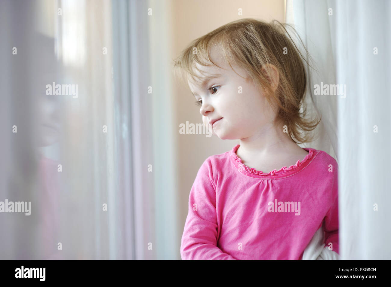 Adorable smiling little girl by the window Stock Photo - Alamy