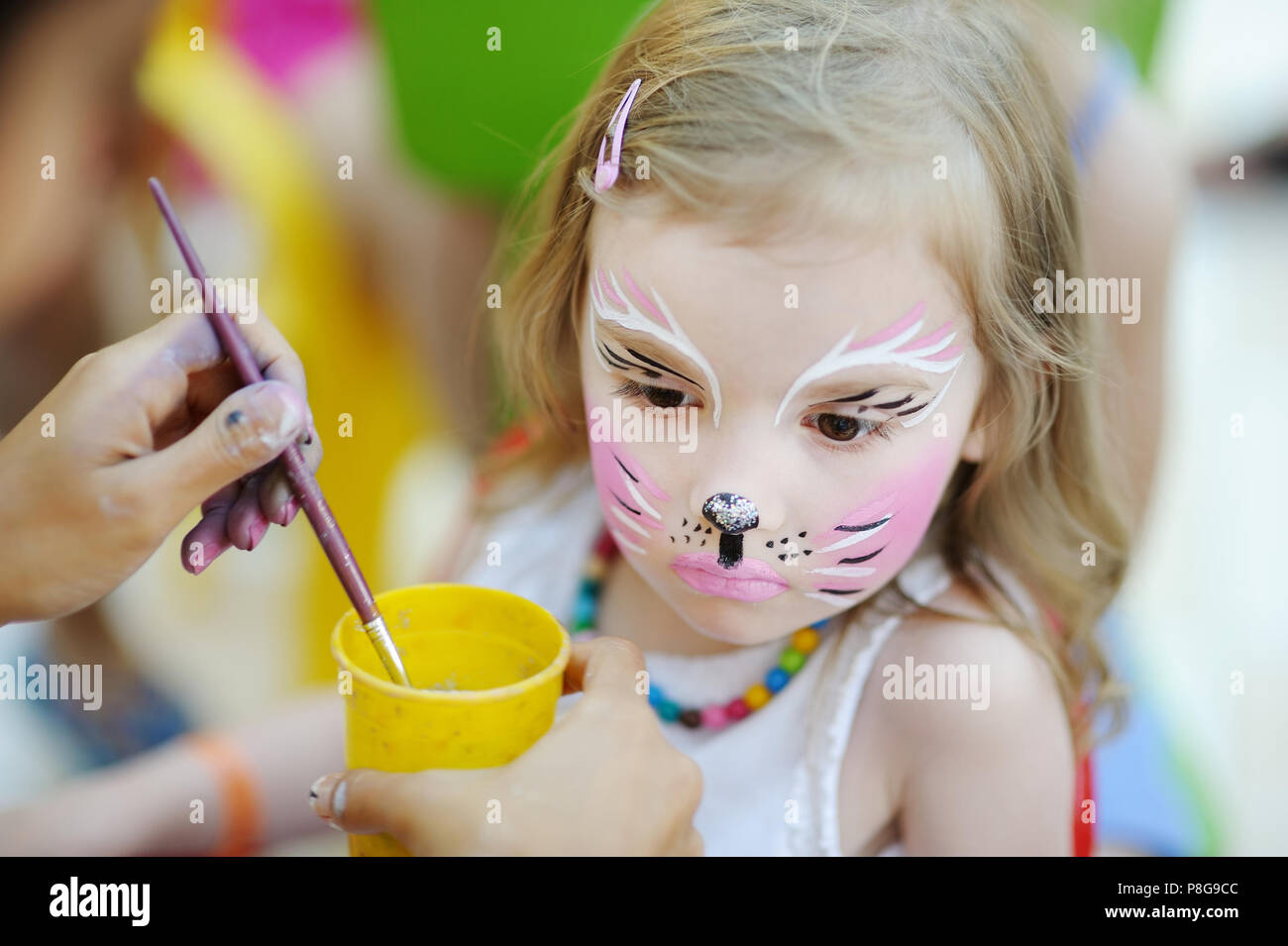 Adorable little girl getting her face painted Stock Photo - Alamy