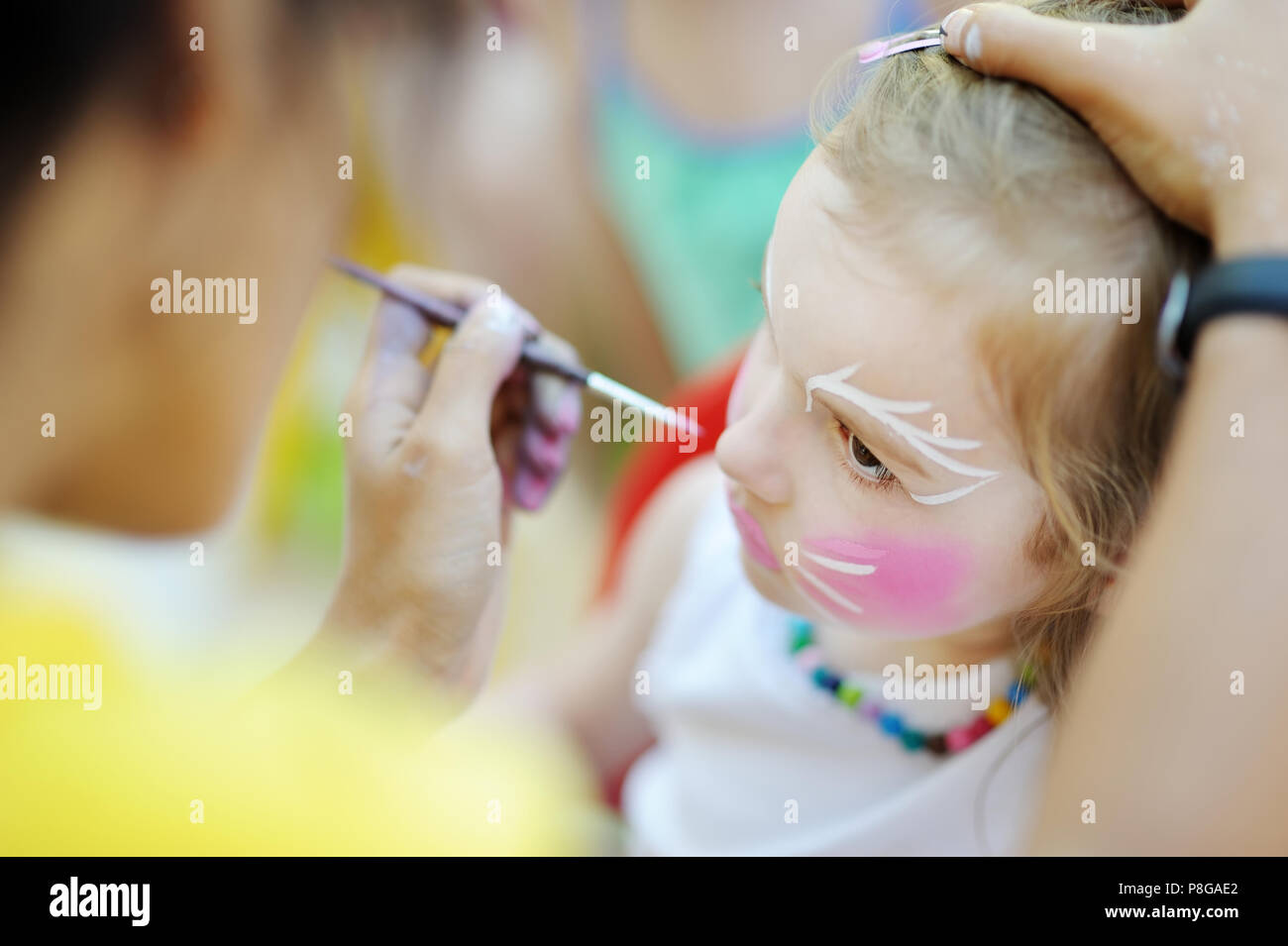 Adorable little girl getting her face painted Stock Photo - Alamy