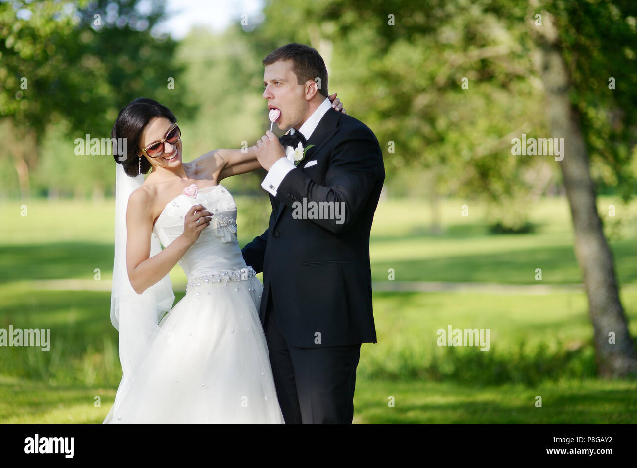 Beautiful bride and groom eating candy Stock Photo - Alamy