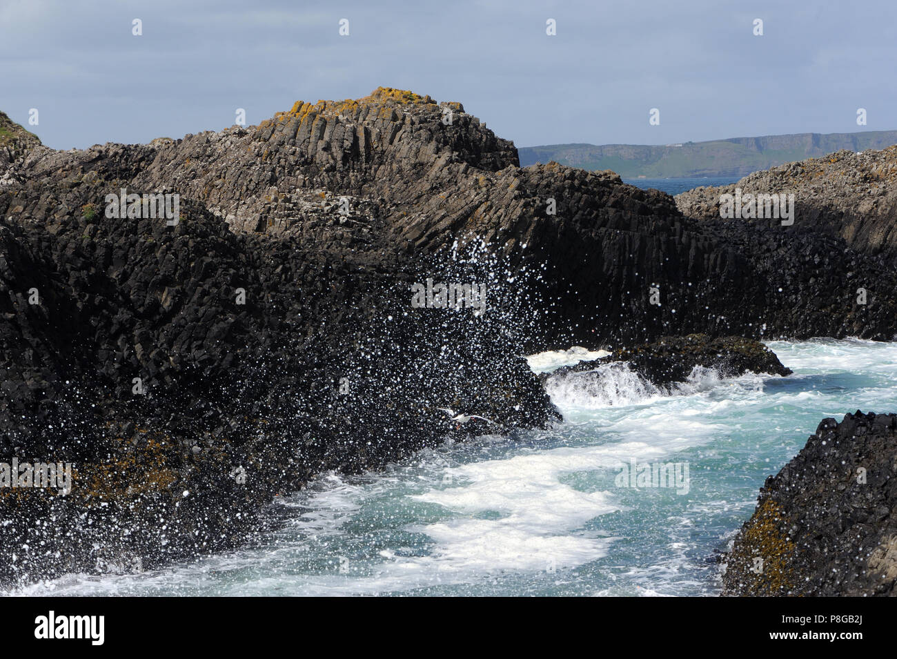 Black basalt cliffs and off shore rocks form the coast of Antrim near ...