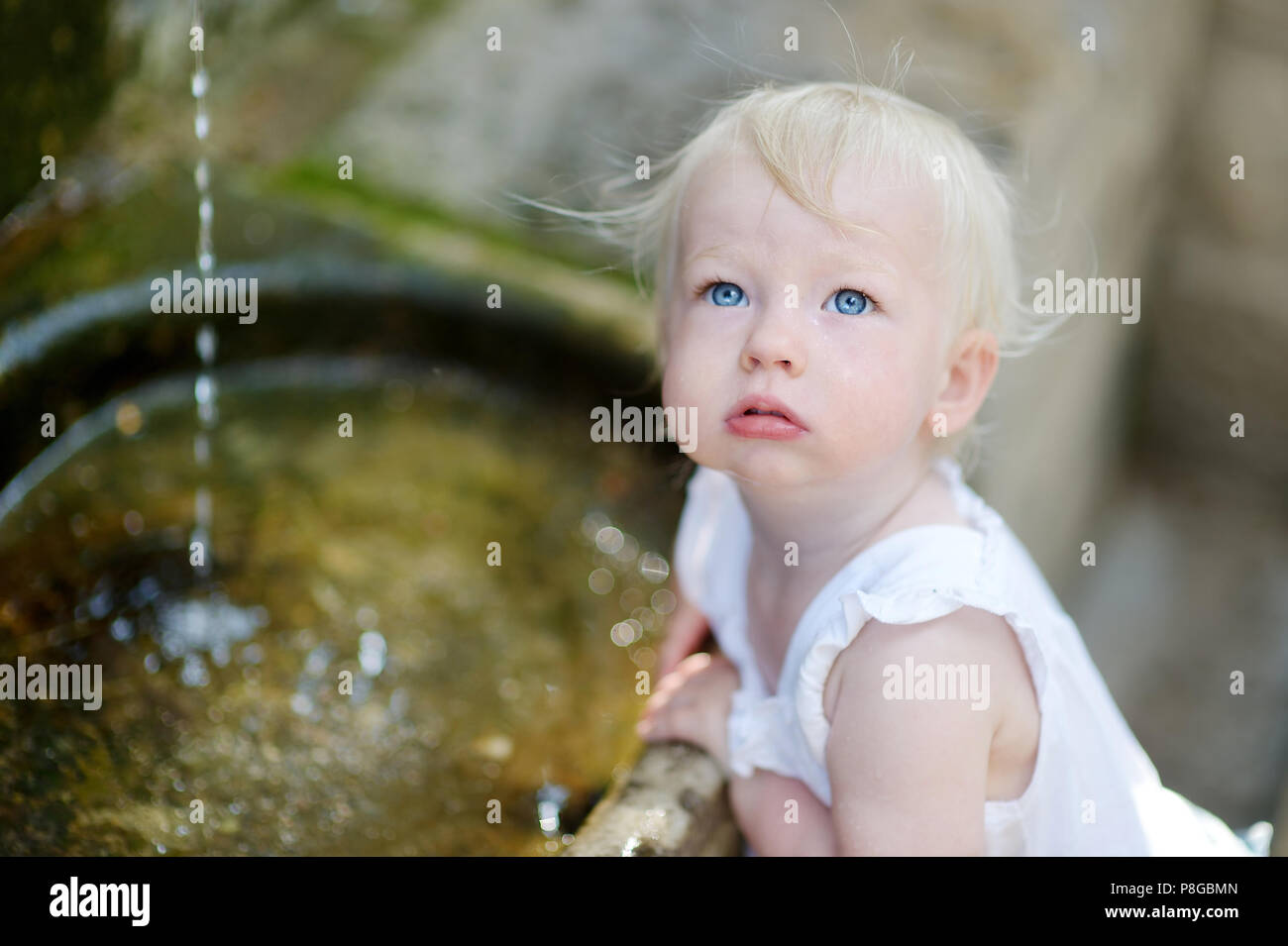 Adorable toddler girl having fun by a city fountain Stock Photo - Alamy
