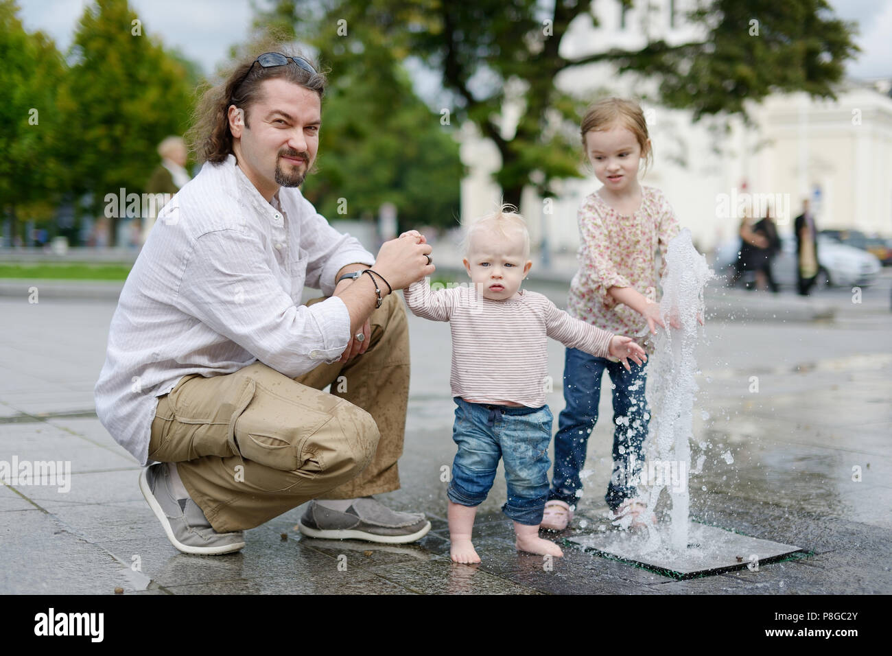 Happy family girl having fun by a city fountain Stock Photo - Alamy